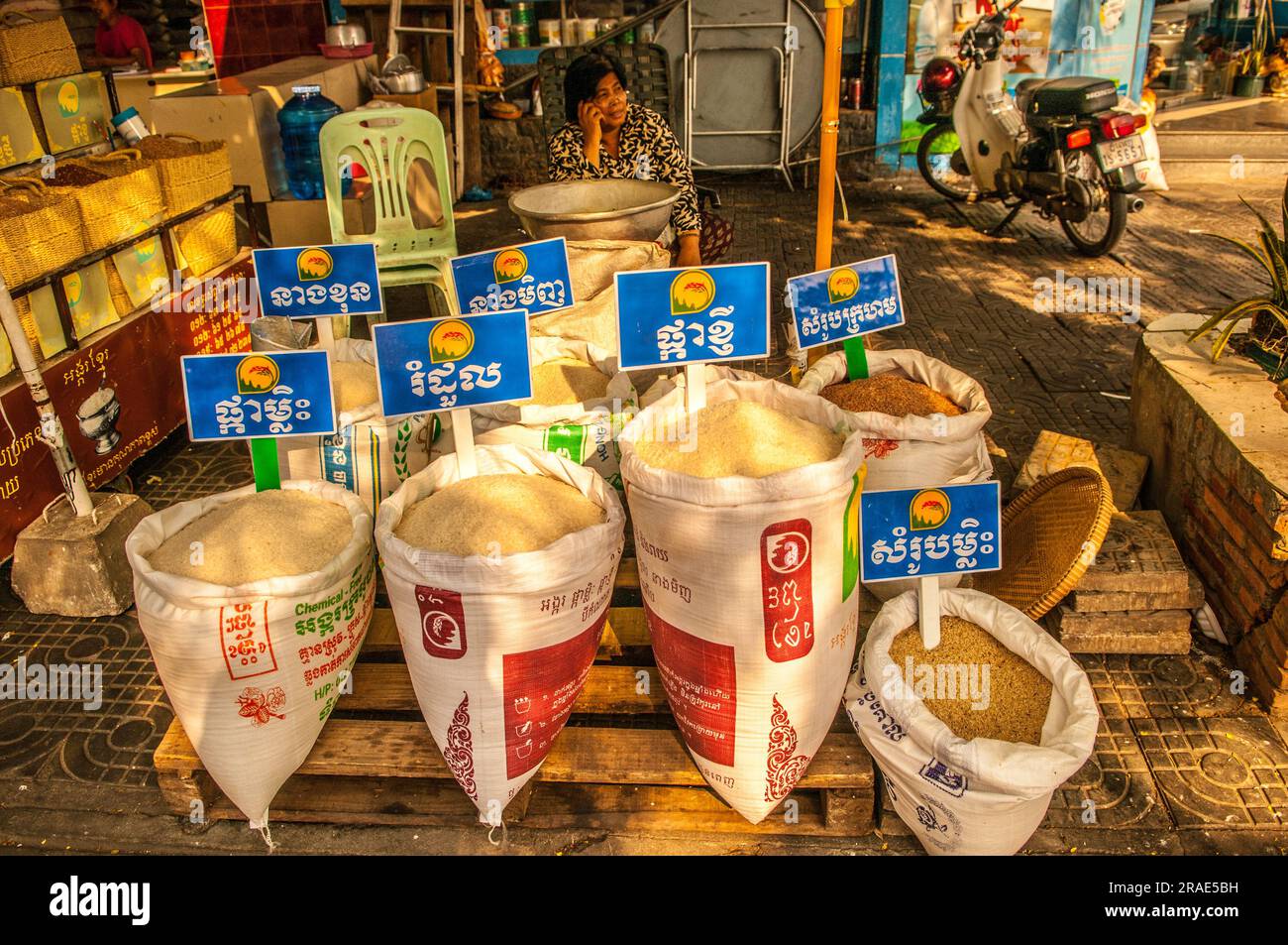 A Cambodian woman selling rice at a local market talks on a cell phone ...
