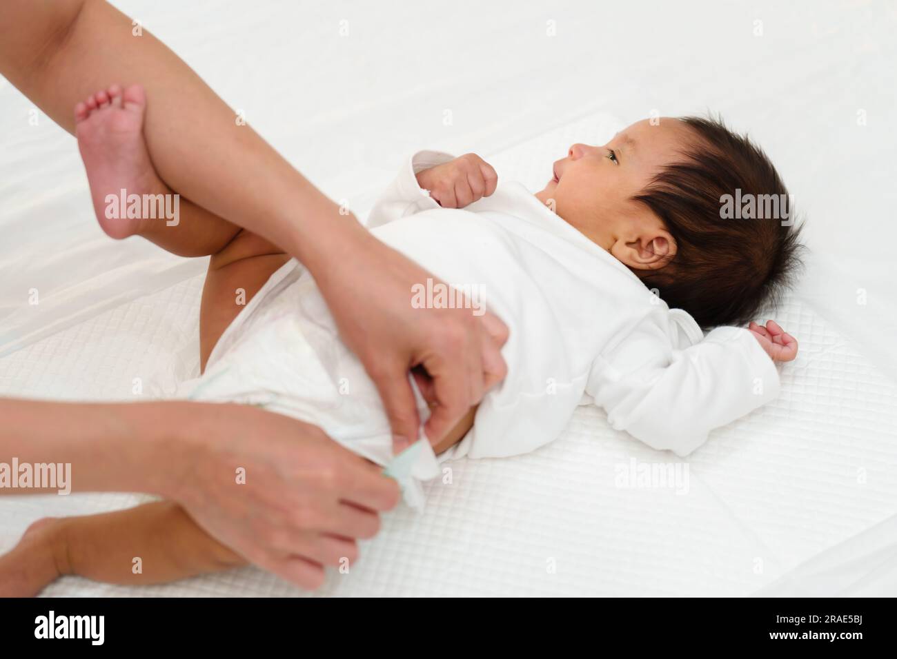 mother changing diaper of newborn baby while lying on a bed Stock Photo ...