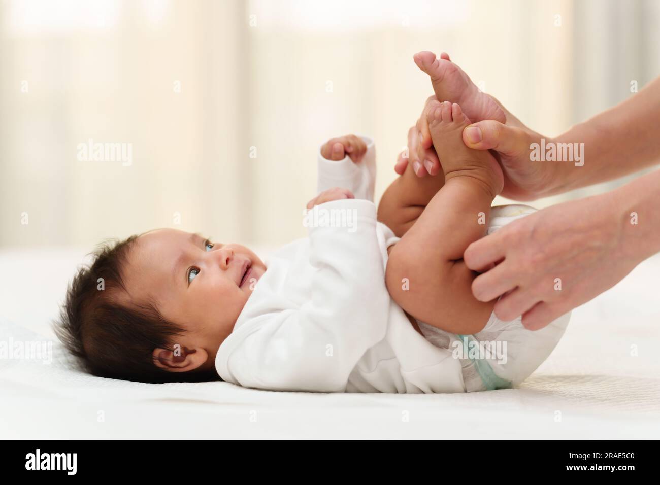 mother changing diaper of newborn baby while lying on a bed Stock Photo ...