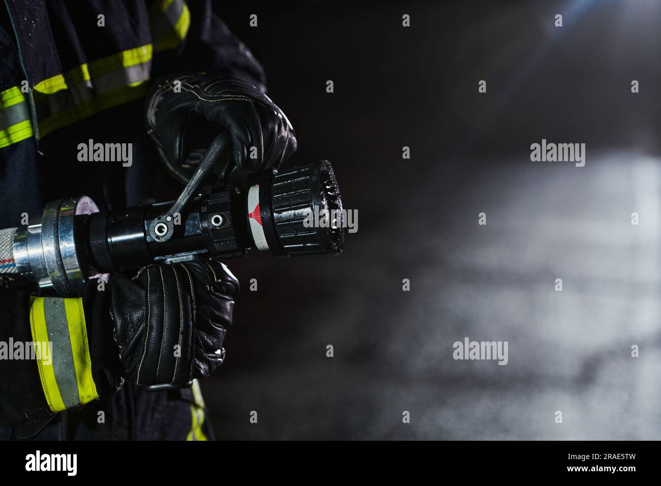 Firefighter using a water hose to eliminate a fire hazard. Team of ...