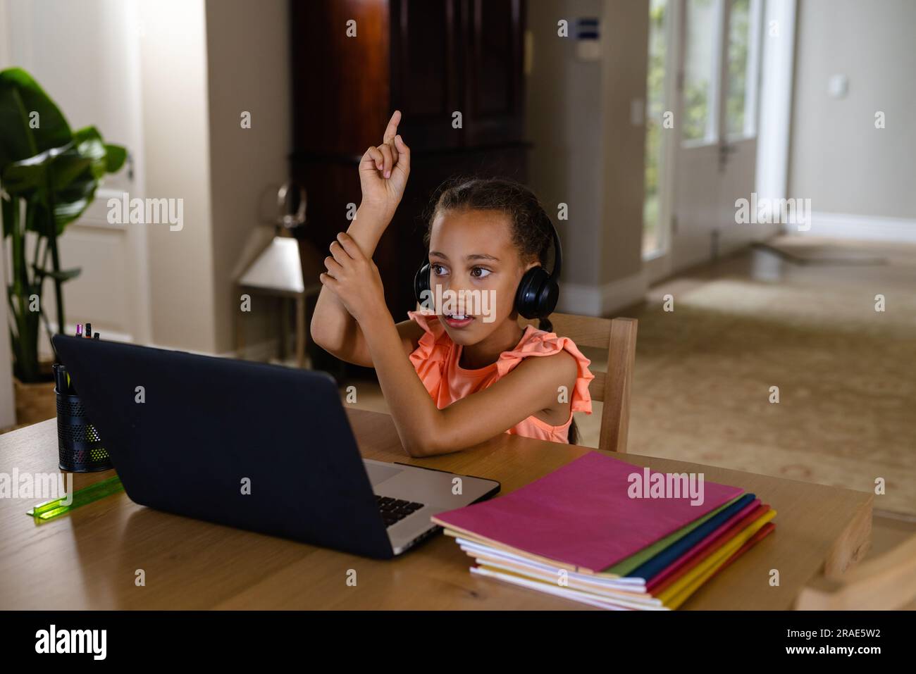 Biracial girl using headphones and laptop for online lesson at home ...