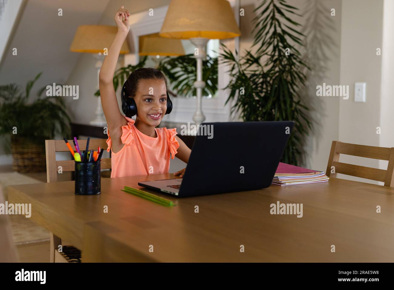 Happy biracial girl using headphones and laptop for online lesson at ...