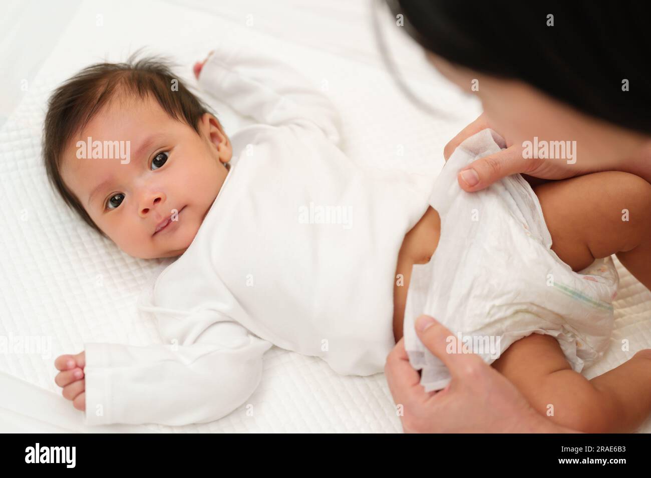 mother changing diaper of newborn baby while lying on a bed Stock Photo ...