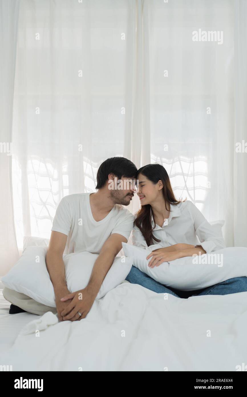 Asian Romantic couple in bed enjoying sensual foreplay Happy sensual young couple lying in bed ...
