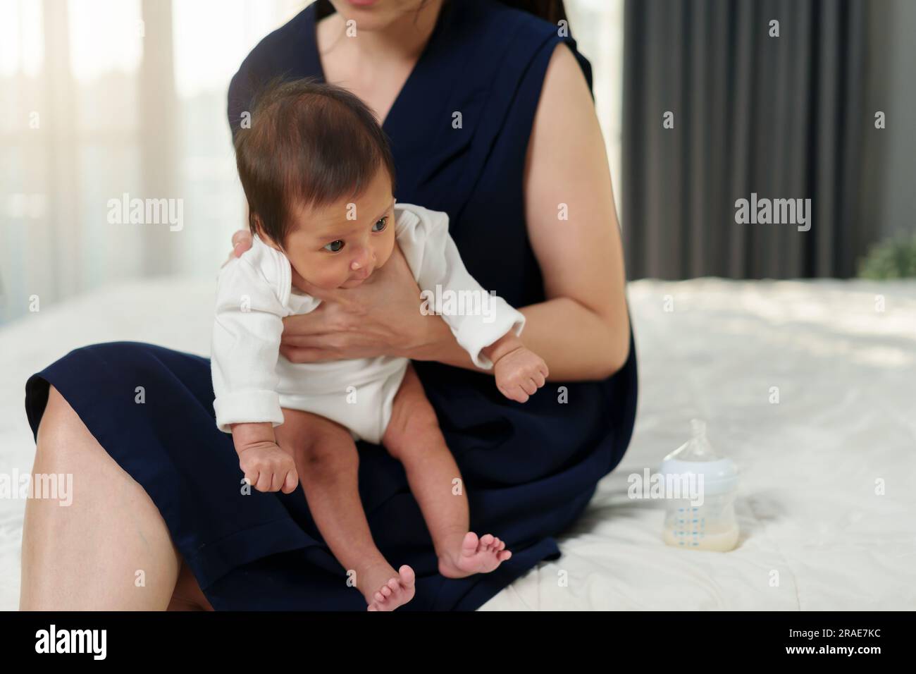 mother holding newborn baby burping in a bedroom after feeding milk ...