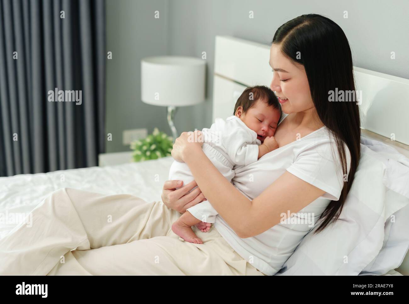 mother holding and consoling her newborn baby to sleeping on a bed Stock Photo - Alamy