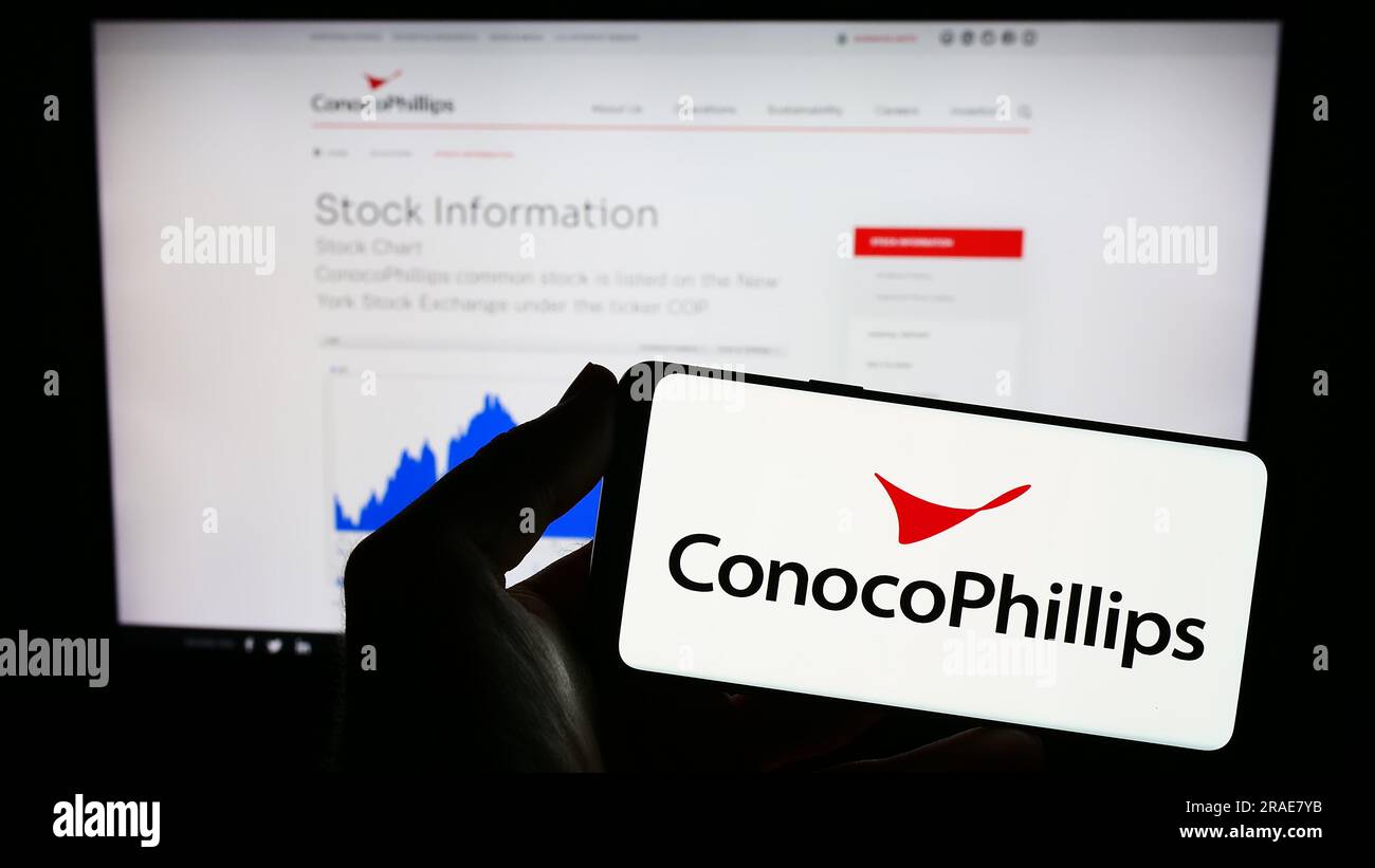 Person holding mobile phone with logo of US oil and gas business ...