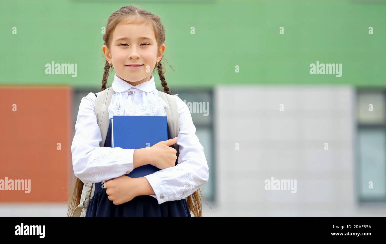 Long-haired schoolgirl with textbook enjoys goes to school Stock Photo ...