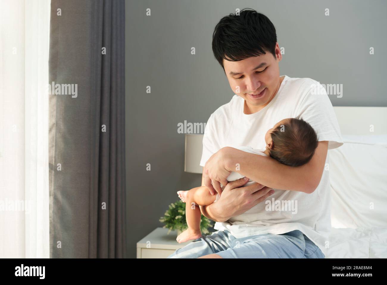 father holding newborn baby on a bed Stock Photo - Alamy