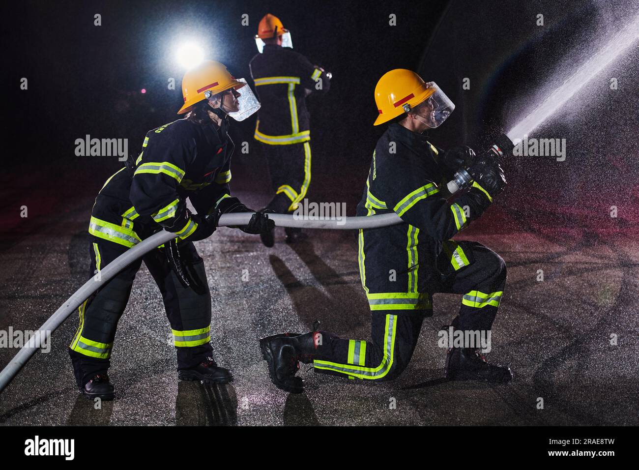 Firefighters using a water hose to eliminate a fire hazard. Team of ...