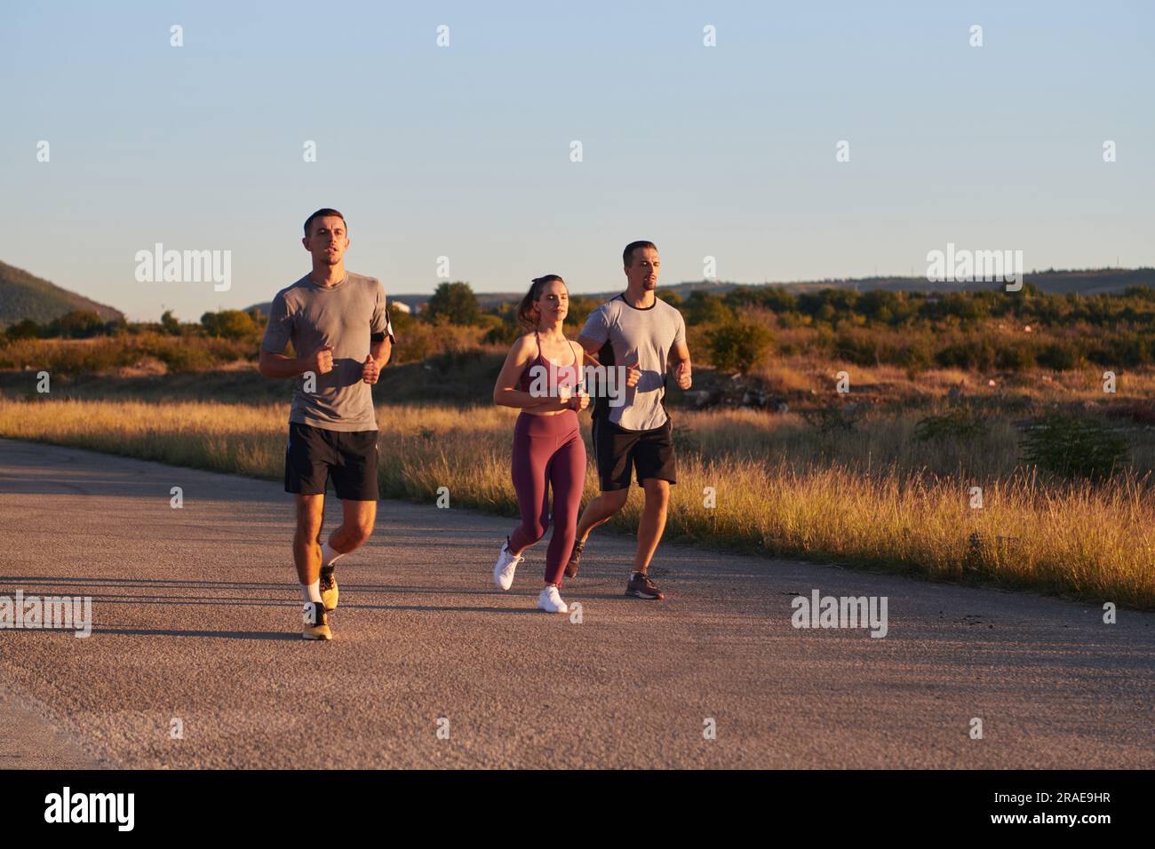 A group of young athletes running together in the early morning light ...