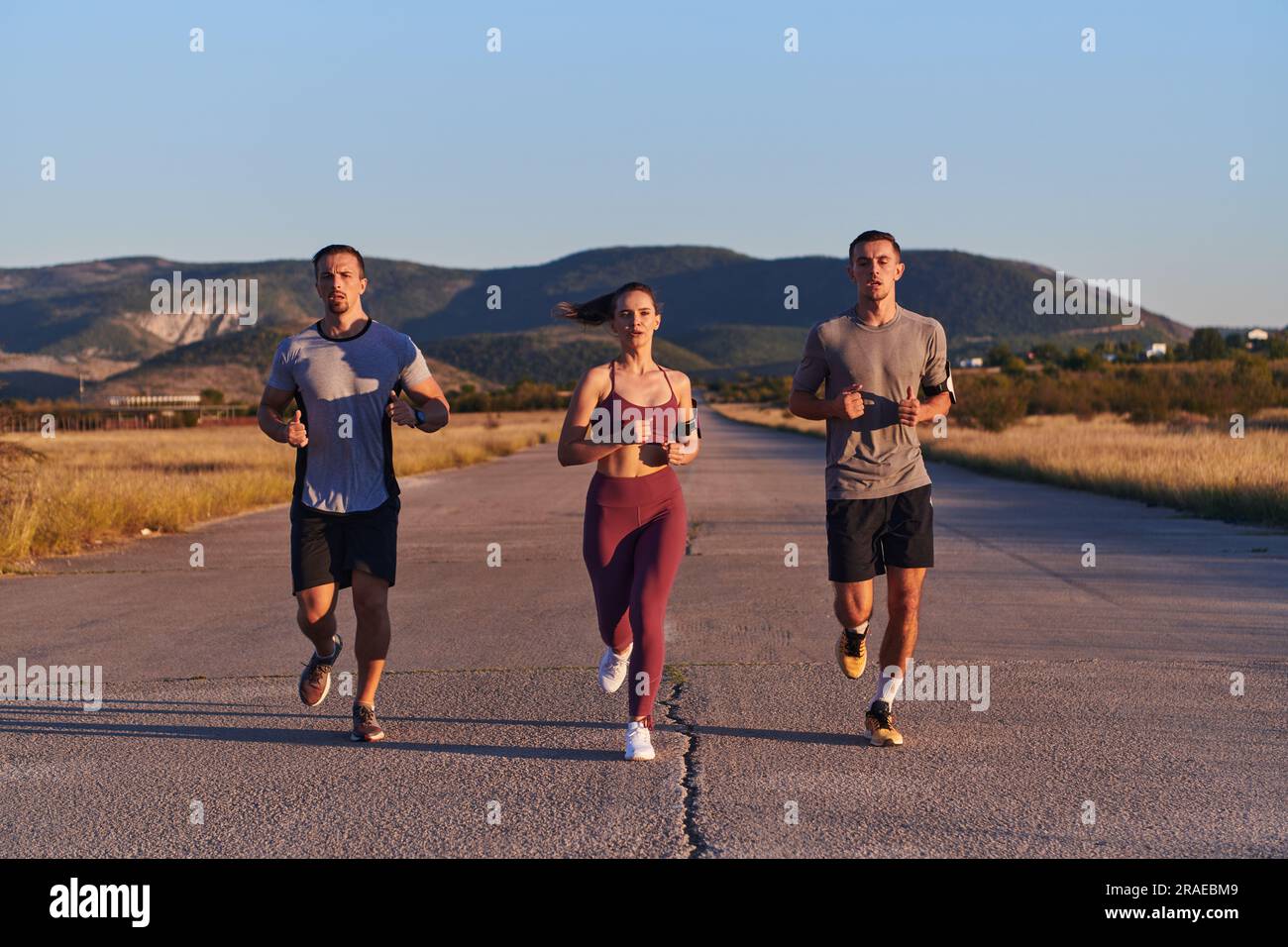 A group of young athletes running together in the early morning light ...