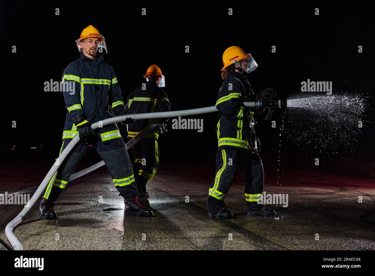 Firefighters using a water hose to eliminate a fire hazard. Team of ...