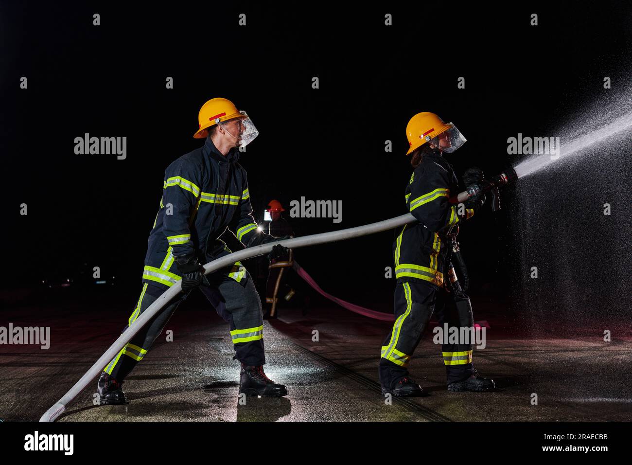 Firefighters using a water hose to eliminate a fire hazard. Team of ...