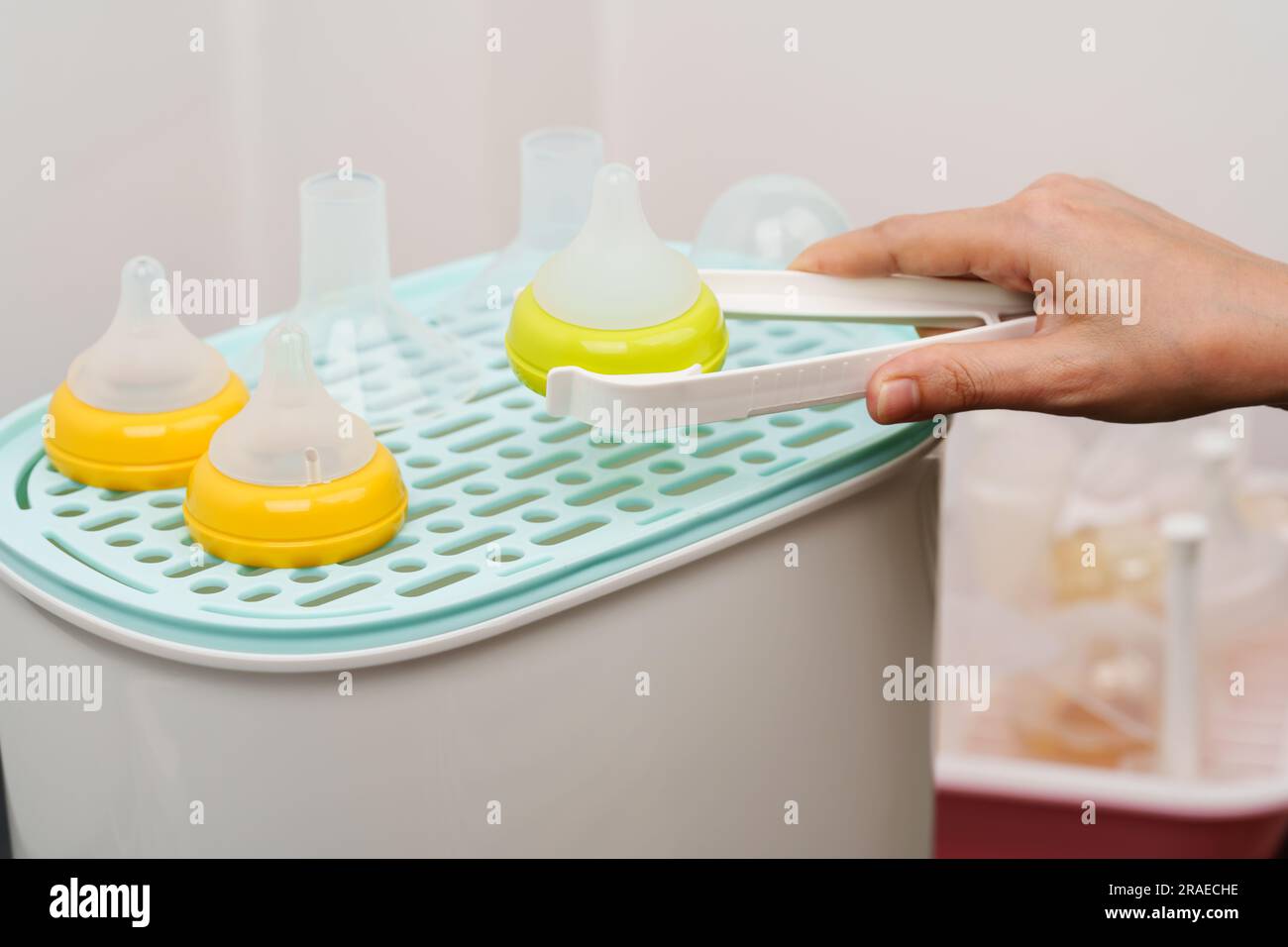 hand of mother feeding baby milk bottle into the Steam sterilizer Stock ...