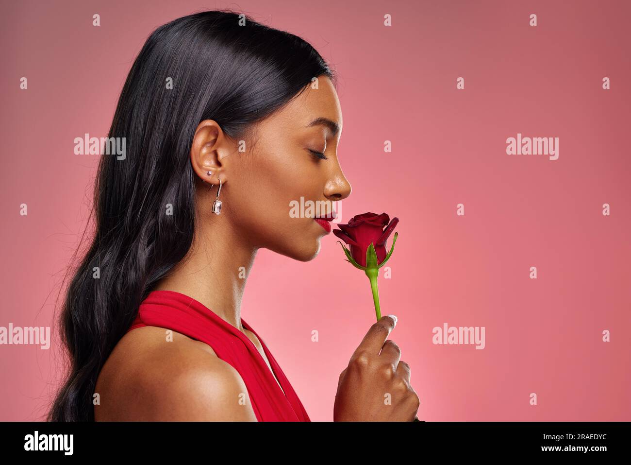 Face, woman and smelling a rose on a studio background for valentines ...