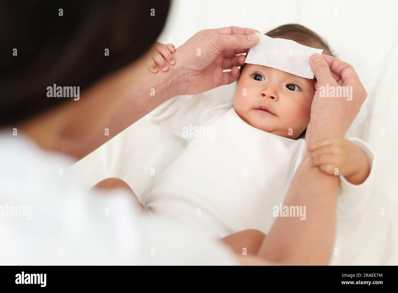 mother putting cool fever jel pad on forehead of sick baby Stock Photo - Alamy