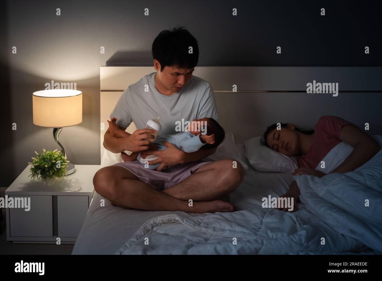 stressed father trying to feeding milk bottle to his crying newborn ...