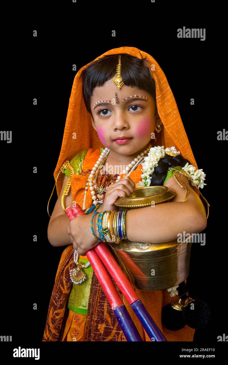 A girl holding a pot in her hip and participating in Janmashtami ...