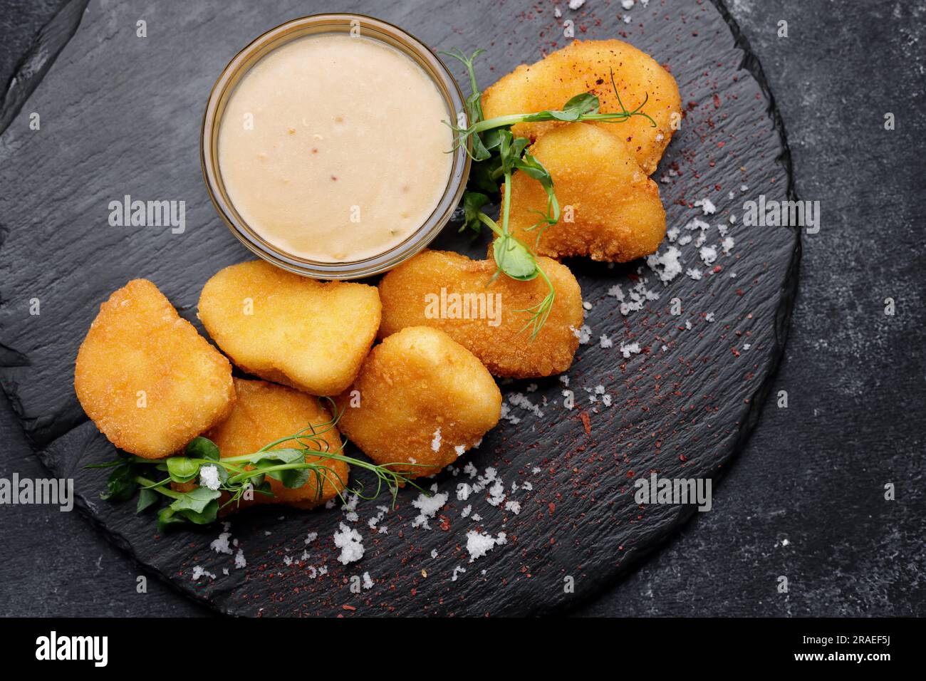 Fried nuggets with sauce and herbs on a black stone. top view Stock ...