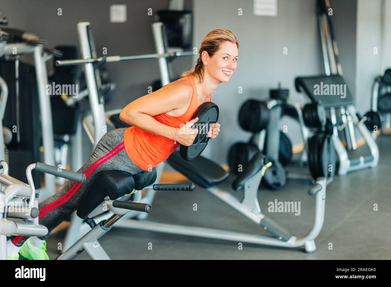 Young fit woman working with heavy disk in gym Stock Photo - Alamy