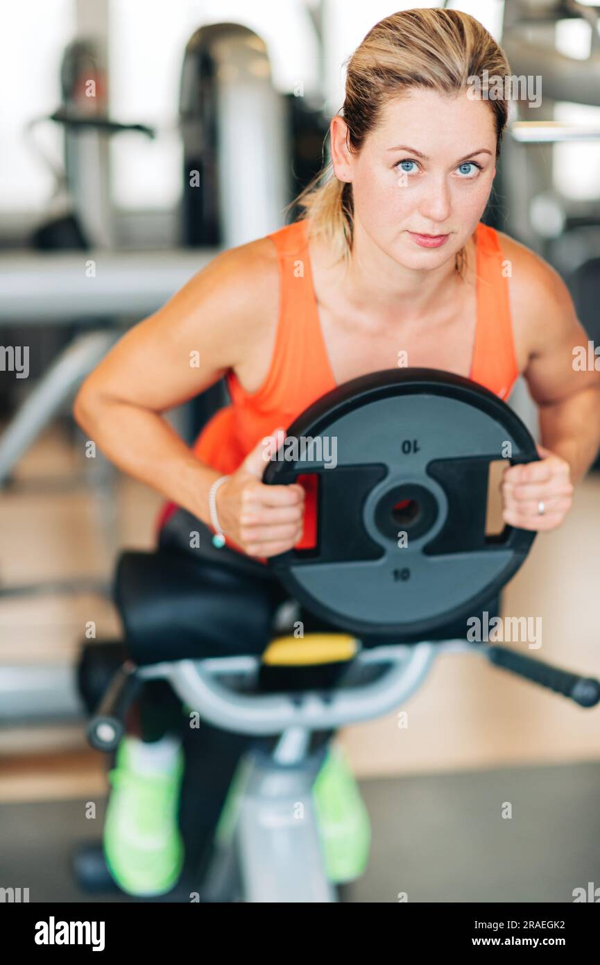 Young fit woman working with heavy disk in gym Stock Photo - Alamy