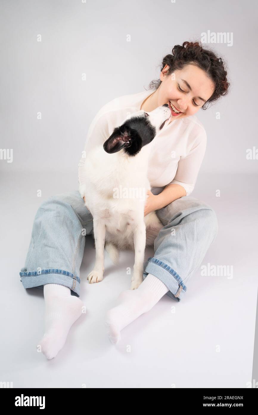 Pet kiss. Smiling young woman hugging her white dog sitting on the floor Stock Photo - Alamy