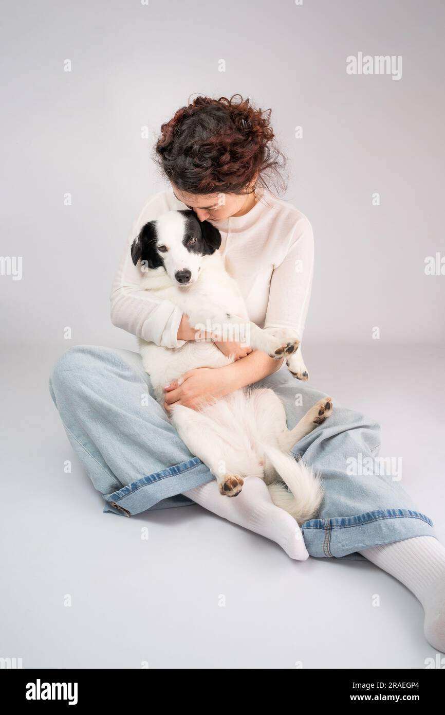 Dog owner and dog cuddling. Hugging young woman and adorable white ...