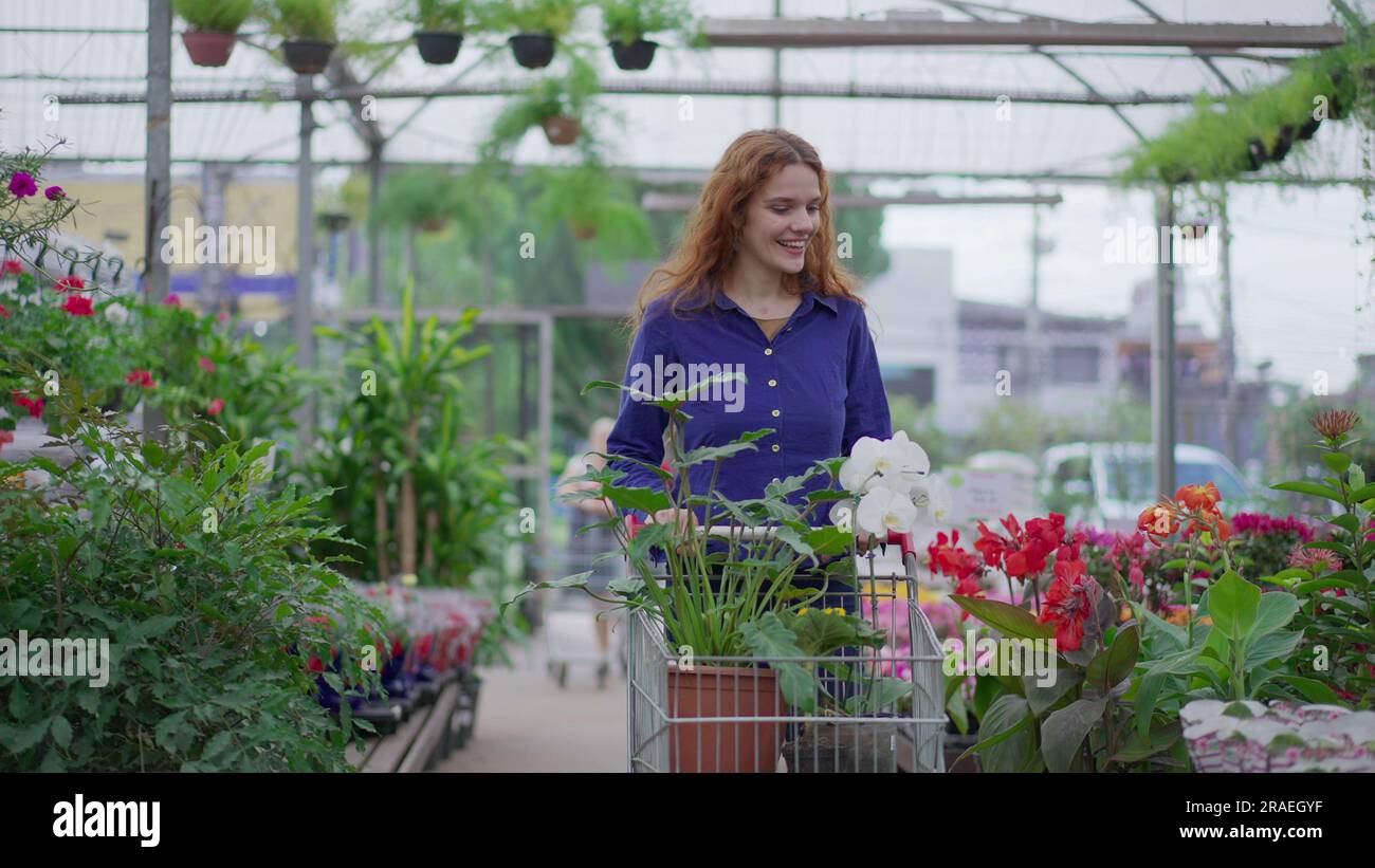Young woman picking flower pot inside horticulture store. Female person ...