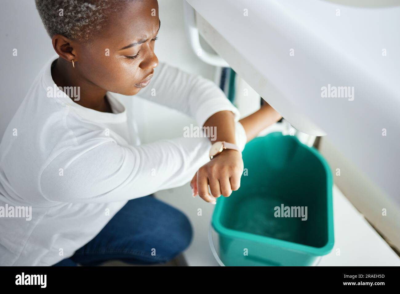 Plumbing, leak and watch with a black woman in the bathroom of her home waiting for repair ...