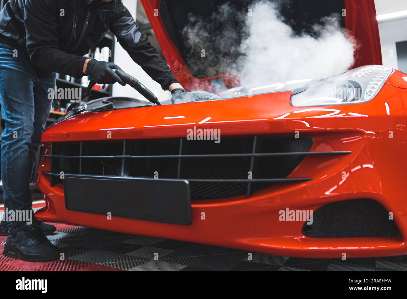 Hot steam deep cleaning of front car lid and engine area. Low angle ...