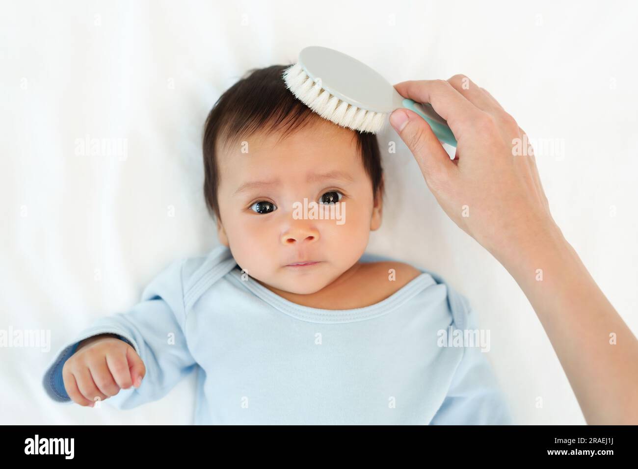 mother combing her newborn baby hair on a bed Stock Photo - Alamy