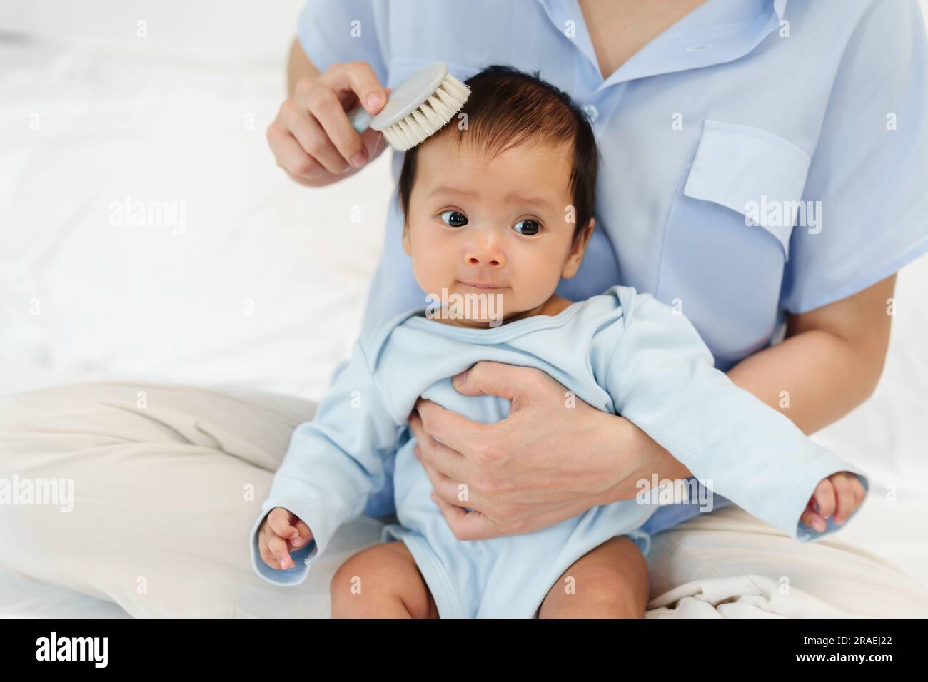 mother combing her newborn baby hair on a bed Stock Photo - Alamy