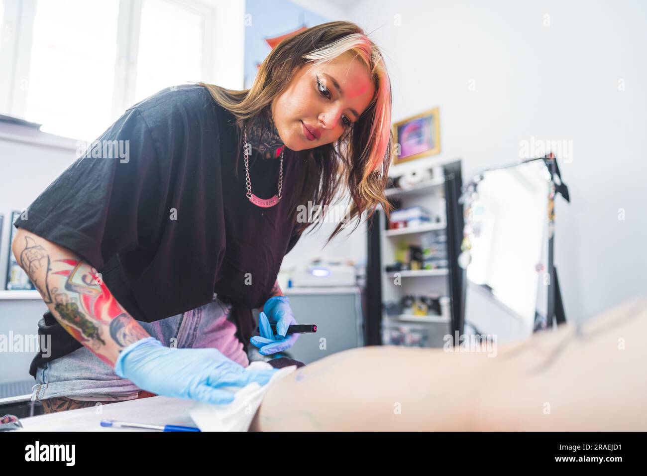 pretty tattoo master drawing on a woman's leg, Freehand technique ...