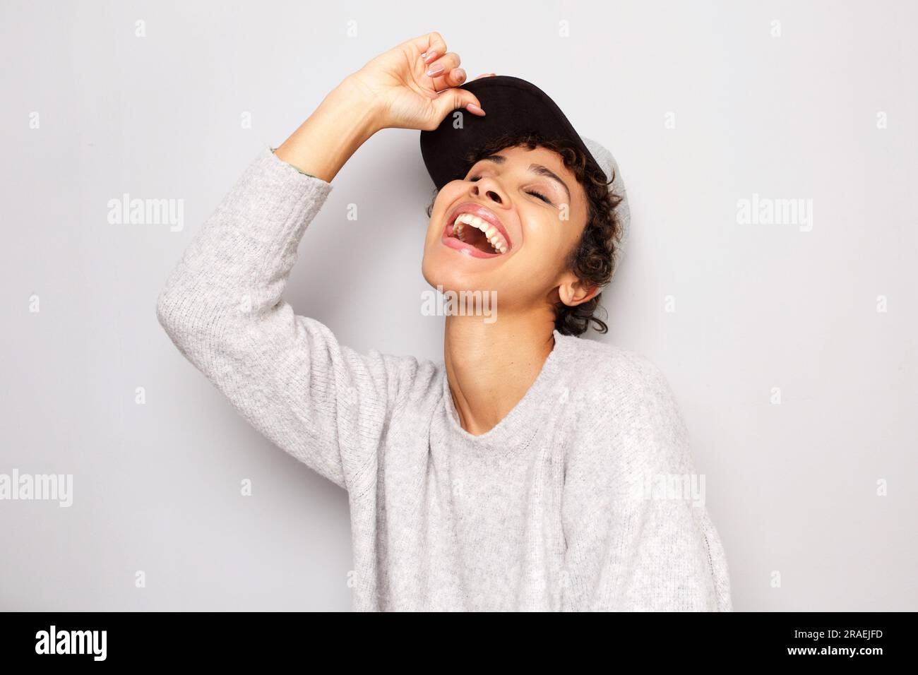 Close up portrait of stylish young woman laughing with cap against ...