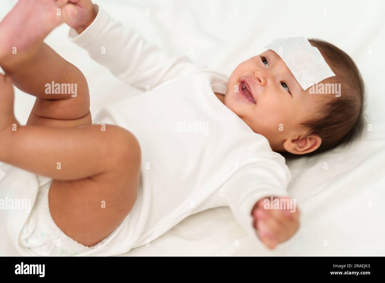 happy sick baby with cool fever jel pad on forehead Stock Photo - Alamy