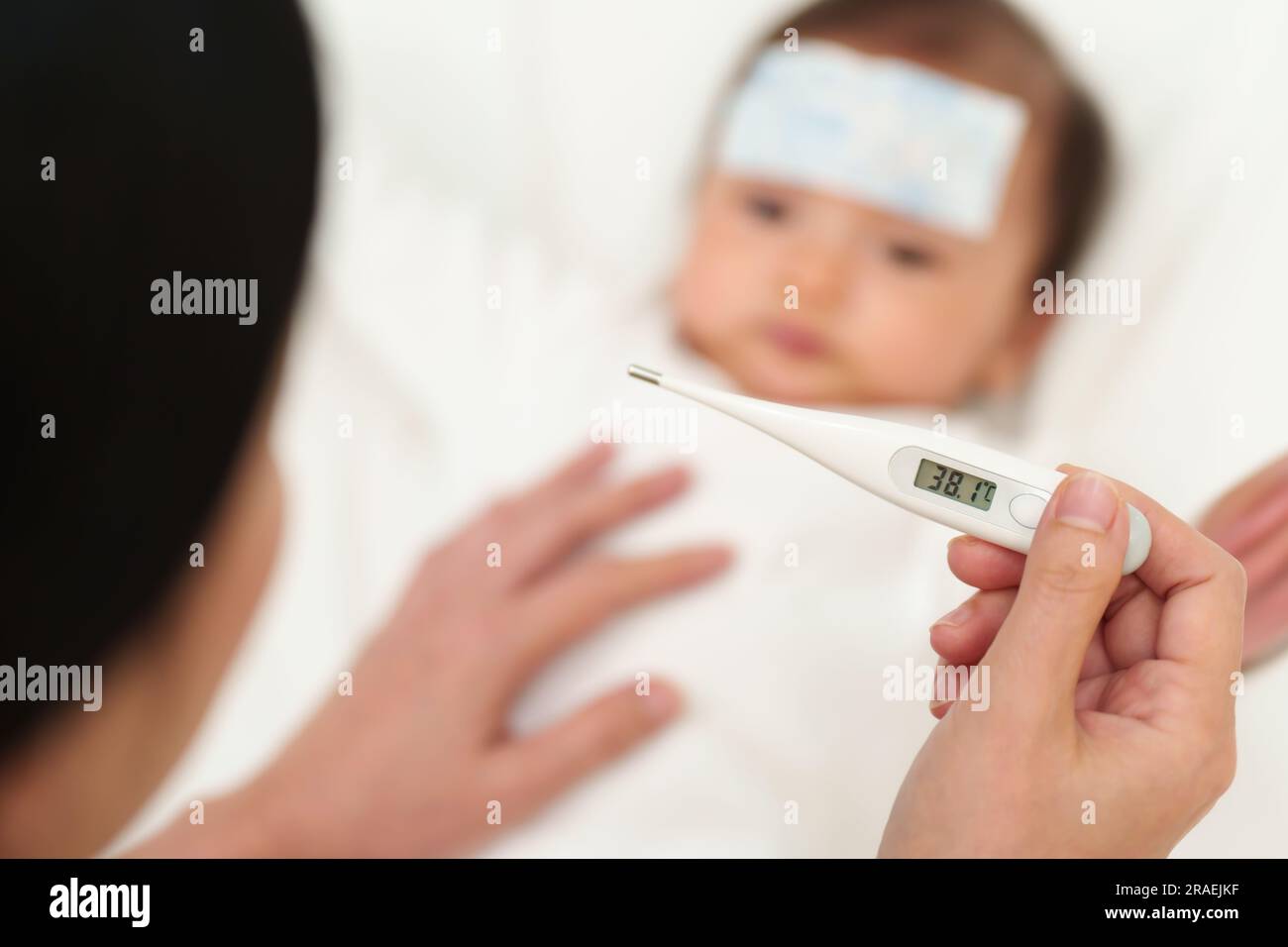 mother measuring temperature of her sick baby with cool fever jel pad ...