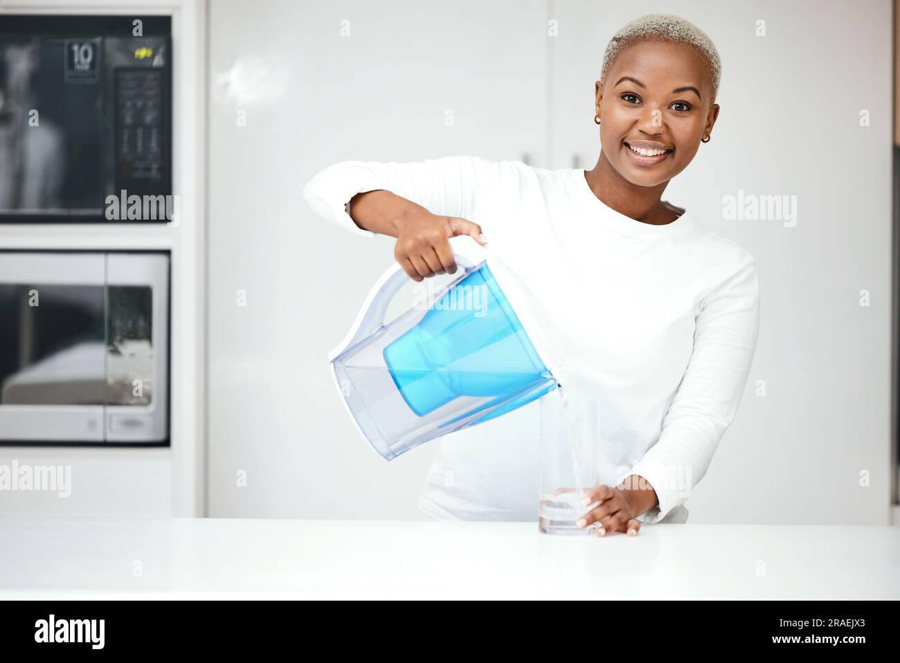 Water, filter and happy woman with jug, glass and portrait in kitchen ...
