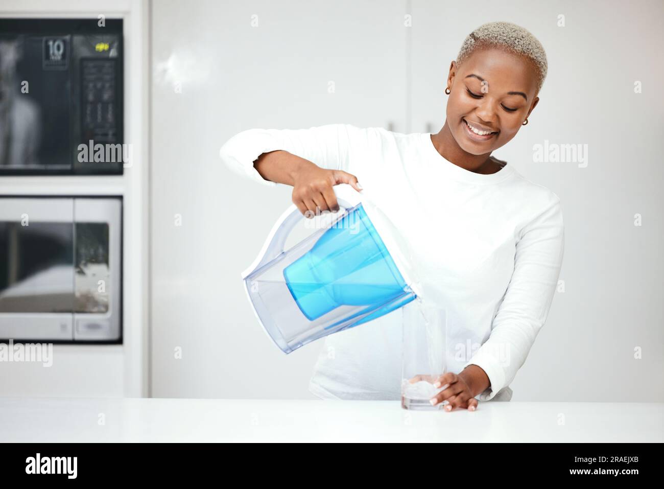 Water, filter and black woman with jug in kitchen to refresh with glass ...