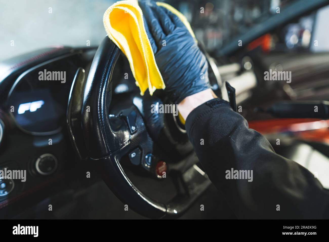 Closeup shot of a hand in black glove holding orange microfibre cloth ...