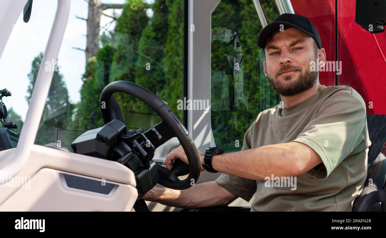 Portrait of worker sits in cabin of rotating telescopic handler machine ...