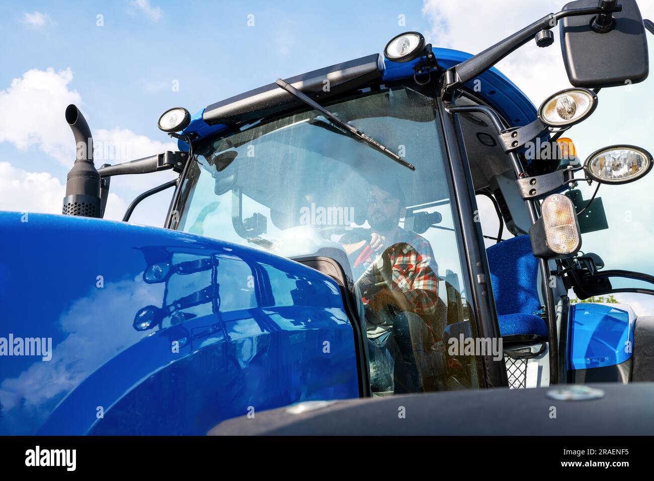 Cabin and windshield of agriculture tractor and tractor driver behind ...