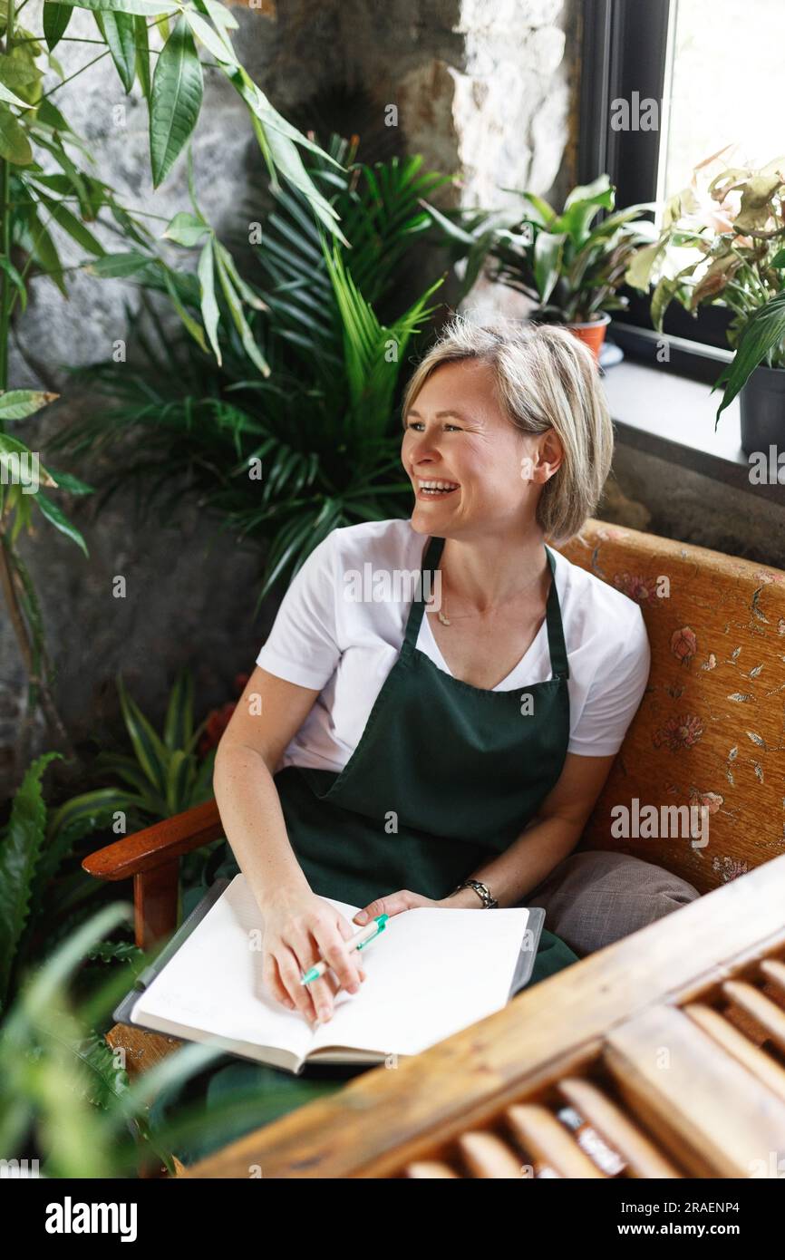 Happy woman gardener writing notes on notebook paper, preparation for ...