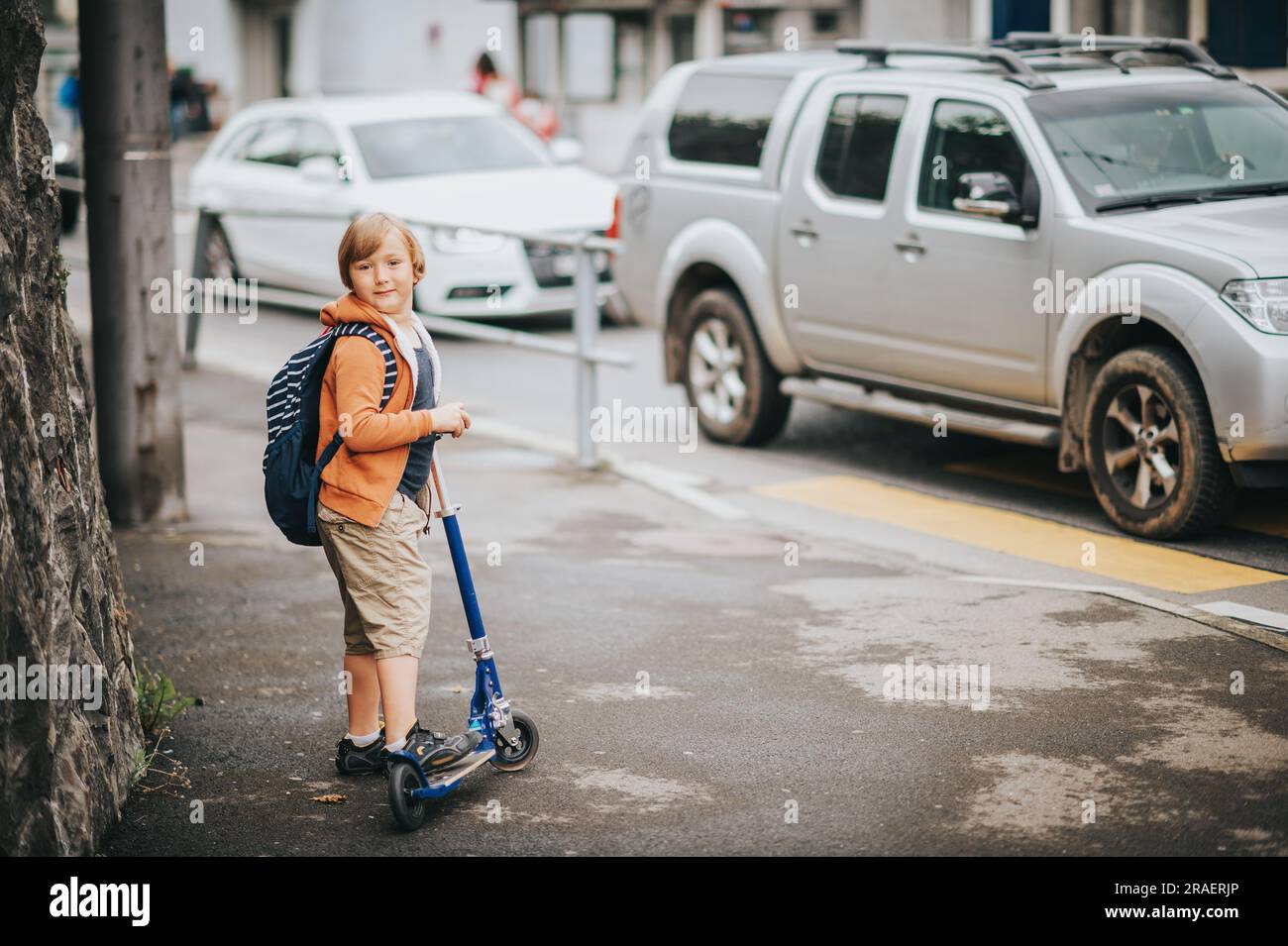 Little boy going to cross the road with car traffic, wearing school ...