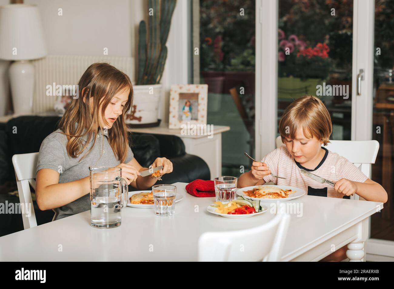 Two kids eating lasagna for lunch, healthy home made meal for children ...