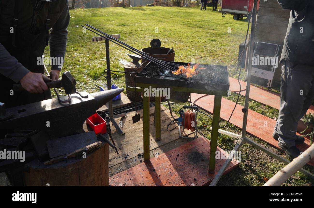 Blacksmith with red-hot iron and open charcoal fire at work Stock Photo ...
