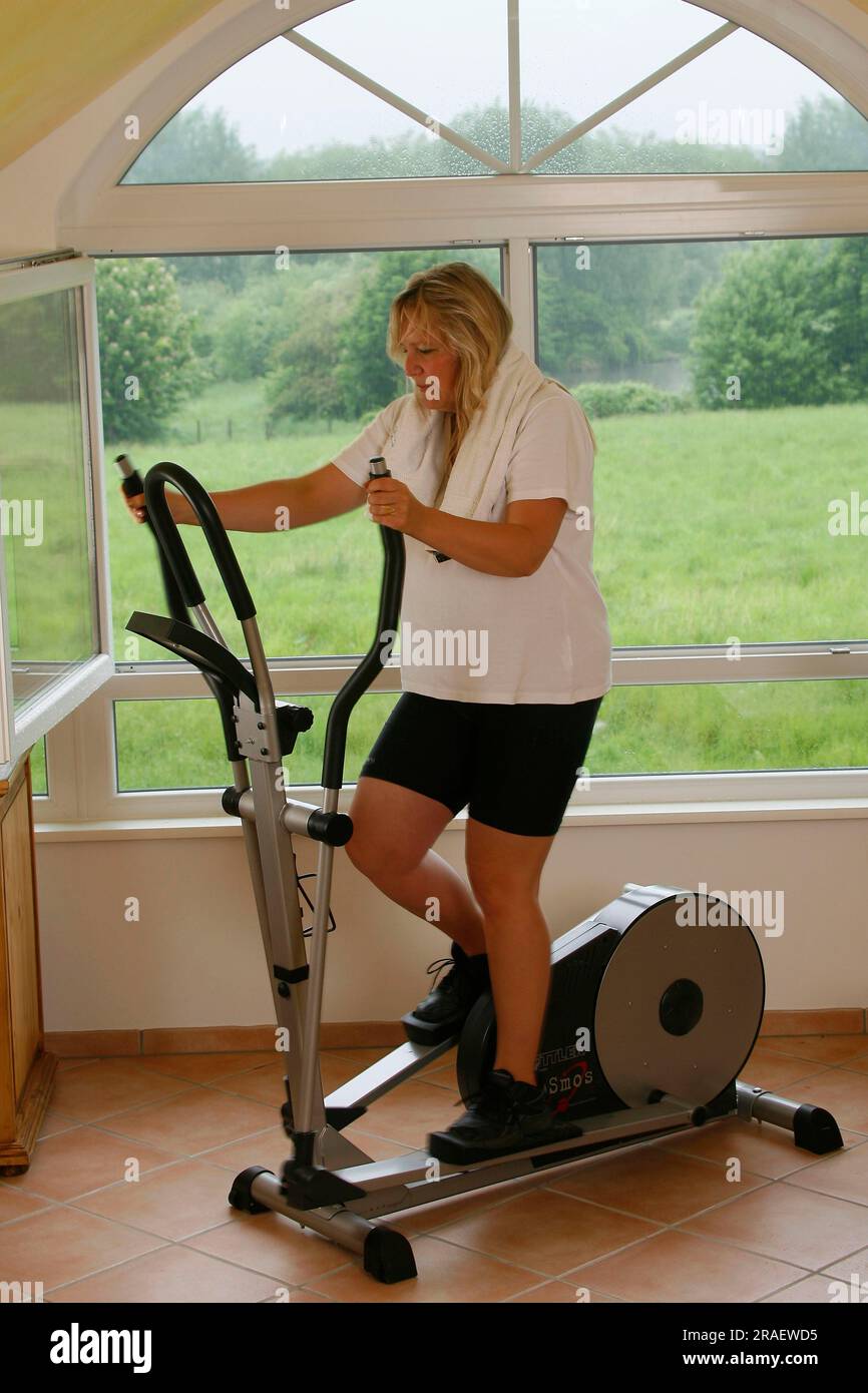 Woman on cross trainer Stock Photo - Alamy