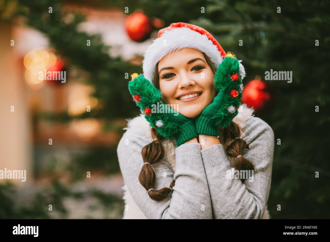 Festive portrait of happy young woman posing outside by the Christmas ...