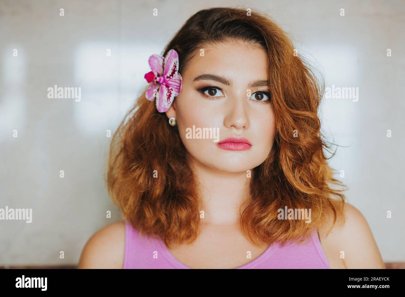 Close up portrait of beautiful mixed race woman, orchid flower behind ...