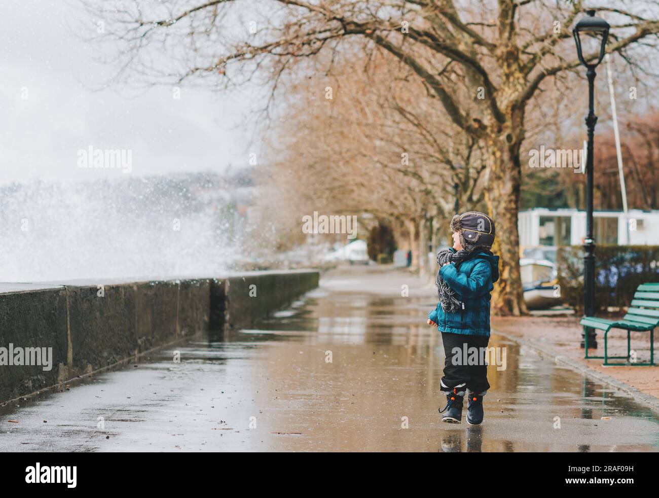 Funny little boy playing outside, running away from lake waves. Early ...